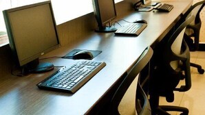 Uma mesa de escritório comprida e estreita com três monitores de computador, dois teclados e um rato.