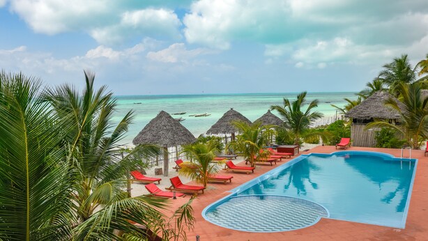 Uma área de piscina com espreguiçadeiras, piscina e vista para o mar.