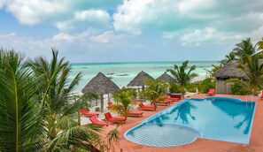 Uma área de piscina com espreguiçadeiras, piscina e vista para o mar.