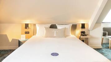 Quarto de hotel com uma cama grande, uma mesa com telefone e uma cadeira.