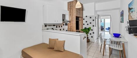 Um apartamento moderno e compacto, com cozinha americana, área de refeições e cama.