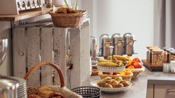 A disposição de um buffet de café da manhã, com diversos alimentos, cestas e pratos empilhados.