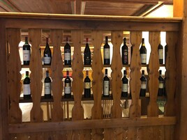 Uma estante de madeira para vinhos, com várias garrafas.