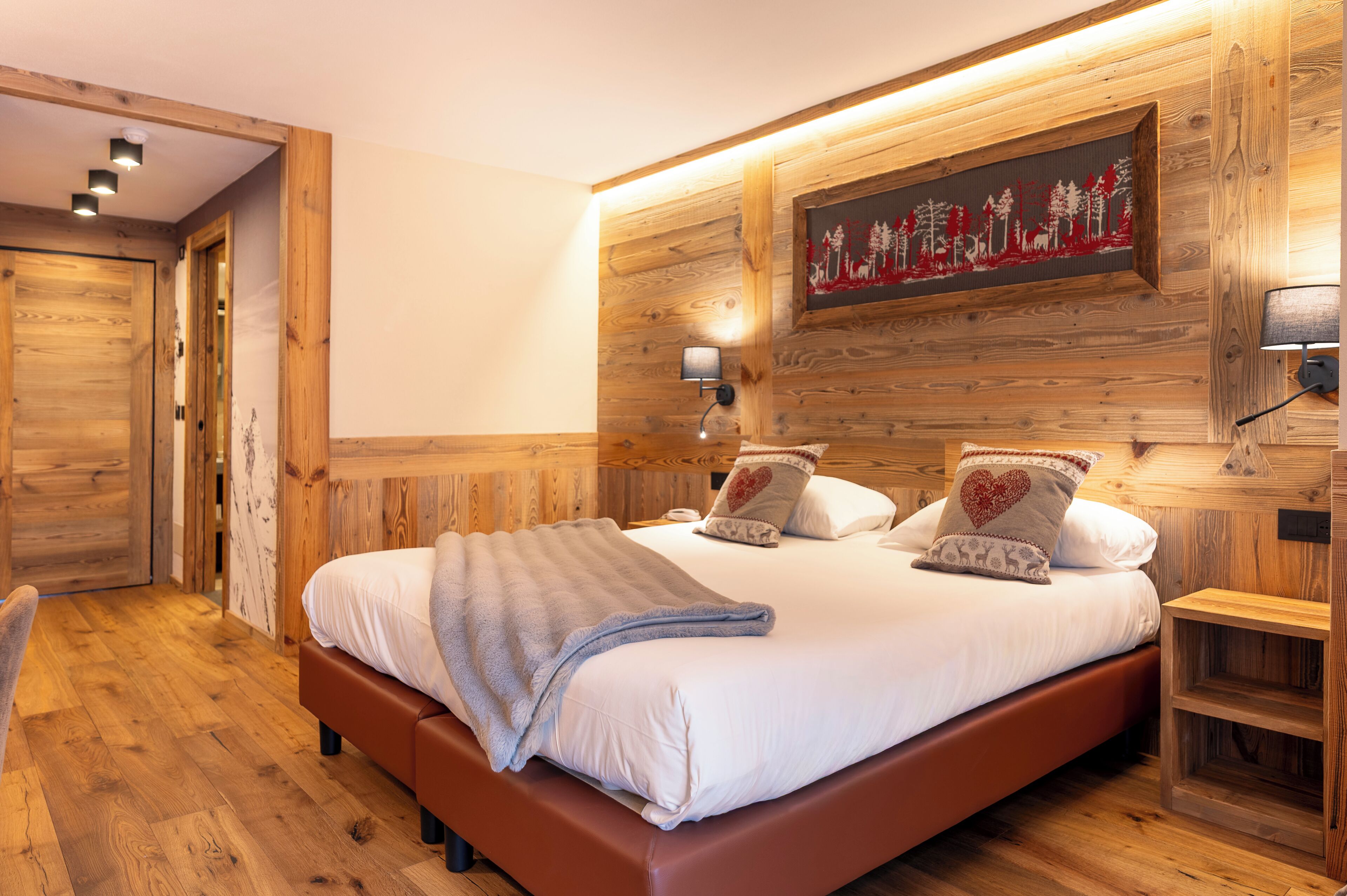 Quarto com painéis de madeira, uma cama, abajures e um quadro na parede.