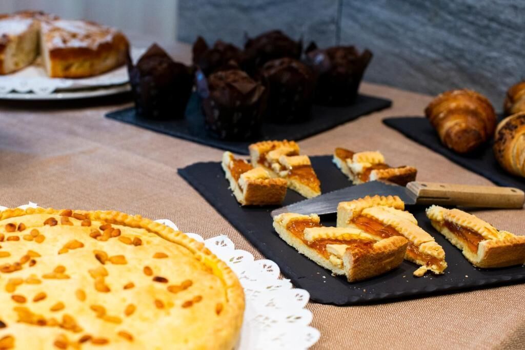 Diversos produtos de panificação sobre uma mesa, incluindo tortas, tarteletes e doces.