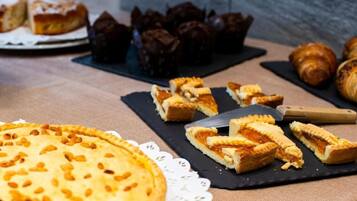 Diversos produtos de panificação sobre uma mesa, incluindo tortas, tarteletes e doces.