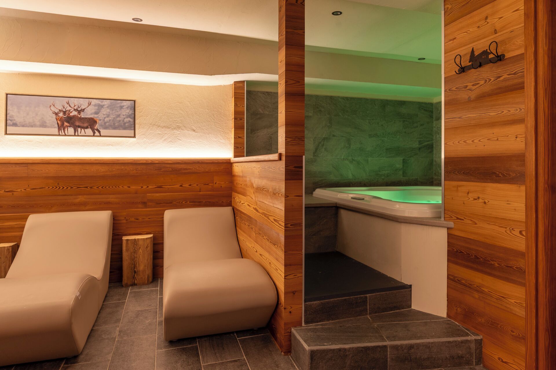 Uma área de spa com paredes de madeira, um quadro de um veado e uma banheira de hidromassagem.