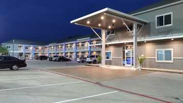 Um hotel com vários andares, entrada coberta e estacionamento.