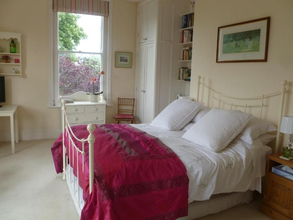 Quarto com cama, janela, estante e escrivaninha.