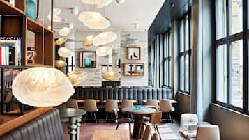Um interior moderno com área de estar, luminárias pendentes e obras de arte emolduradas nas paredes.