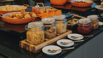Buffet com diversos alimentos e utensílios de servir.