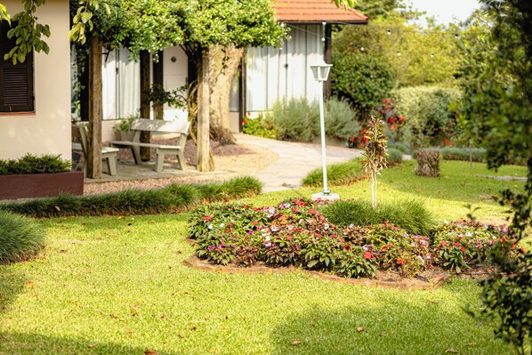 Um jardim bem cuidado com um caminho que leva a um edifício de fachada branca e telhado vermelho.