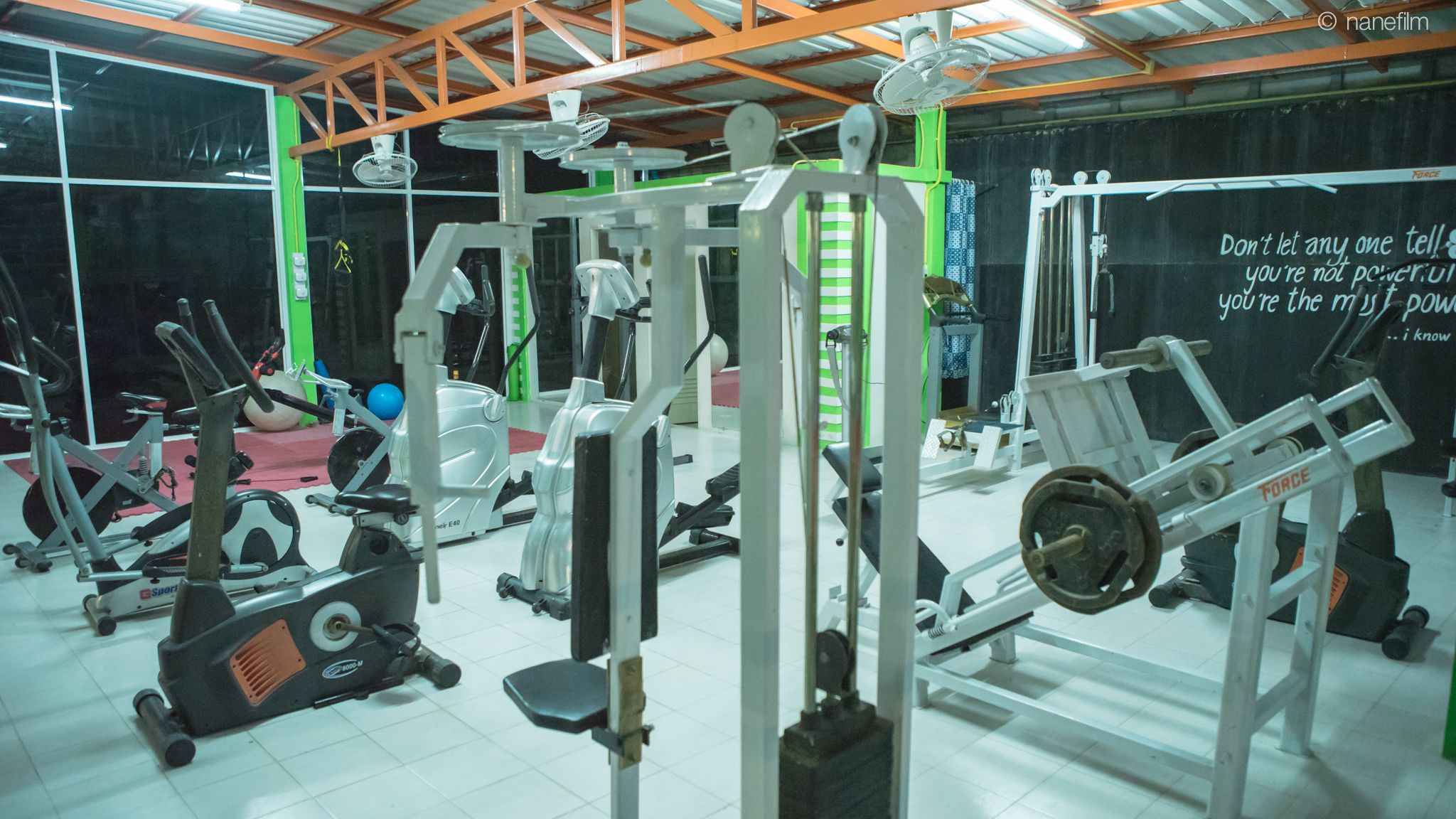 Uma academia com diversos equipamentos de exercício, incluindo esteiras, aparelhos de musculação e uma máquina de remo.