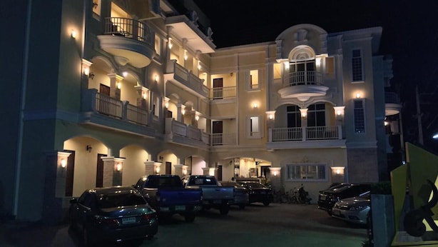 Um hotel com vários andares, varandas e estacionamento.