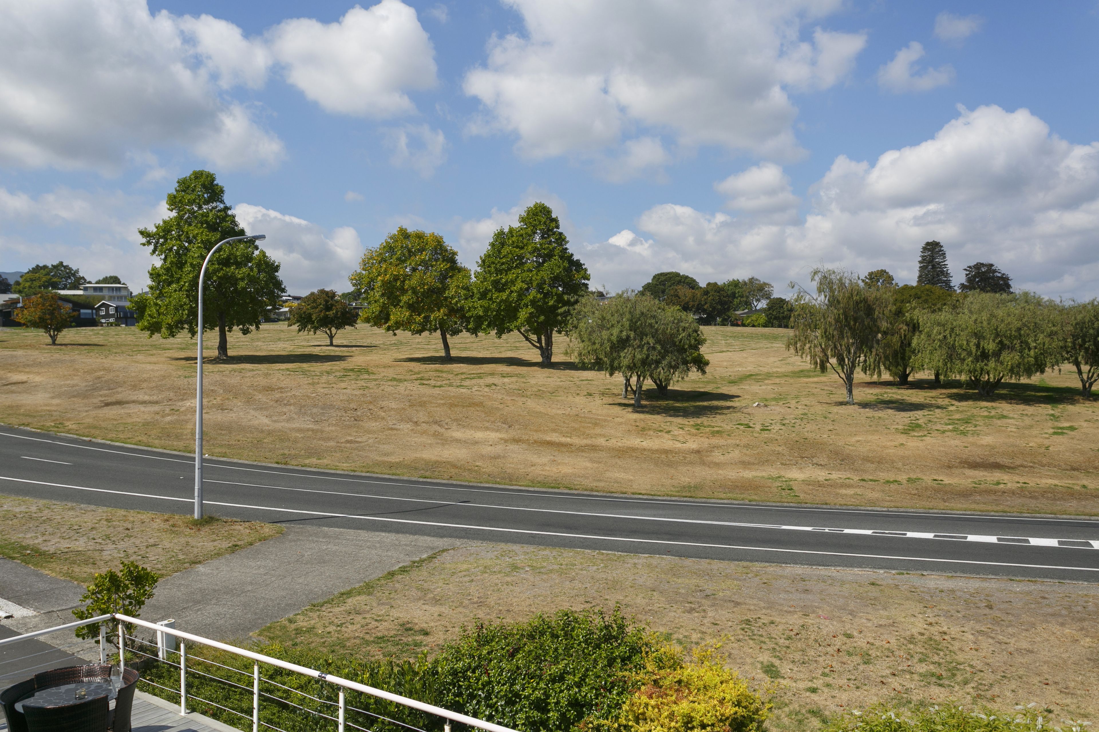 Uma estrada com calçada e árvores ao fundo.