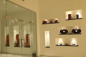 Interior moderno com porta de vidro, piso de mármore e prateleiras fixas com objetos decorativos.