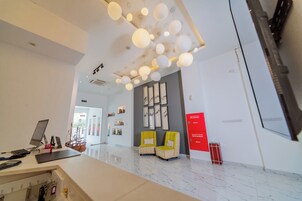 Uma área de recepção moderna, com balcão, cadeiras e uma parede decorada com quadros.