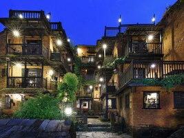 Uma viela estreita ladeada por edifícios altos com varandas, iluminada por postes de luz.