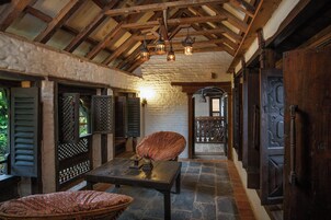 Um interior rústico com vigas de madeira aparentes, soalho de pedra e mobiliário tradicional.