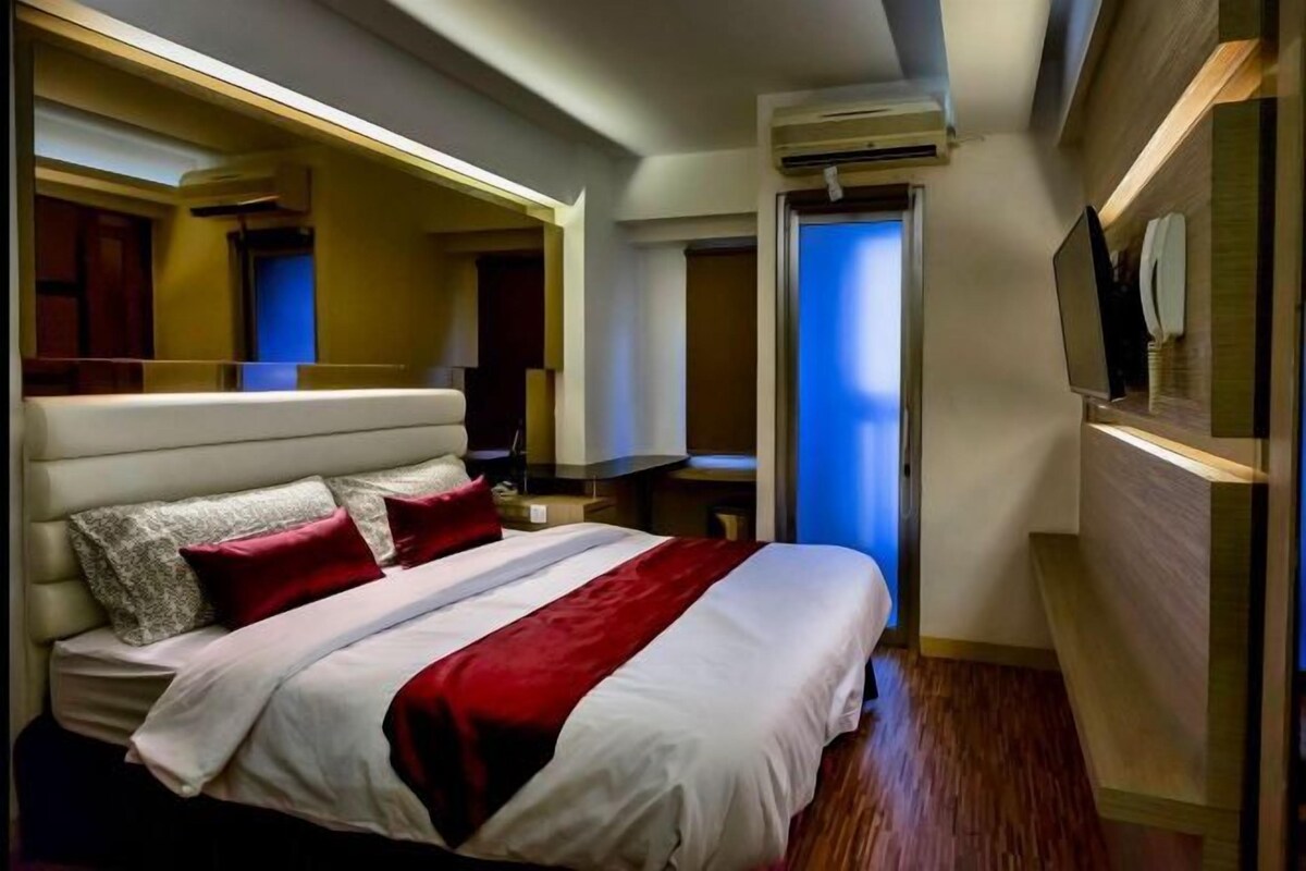 Quarto de hotel com uma cama grande, uma escrivaninha e um espelho.