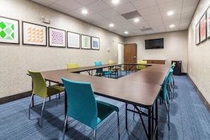 Uma sala de conferência com uma mesa comprida, cadeiras verde-água e obras de arte emolduradas nas paredes.