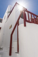Um edifício branco com uma escadaria vermelha e um céu iluminado pelo sol.