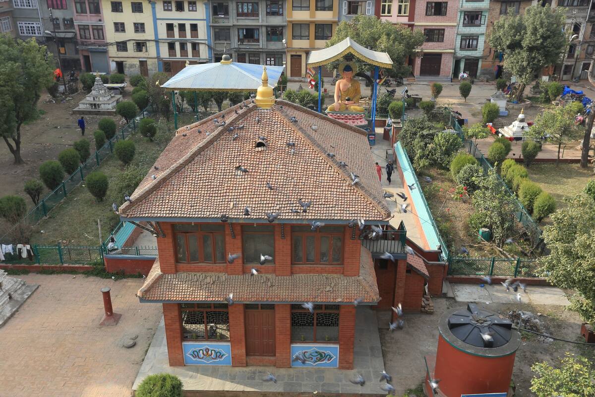Um edifício tradicional com telhado em telhas, um pátio central e uma estátua sobre um pedestal.