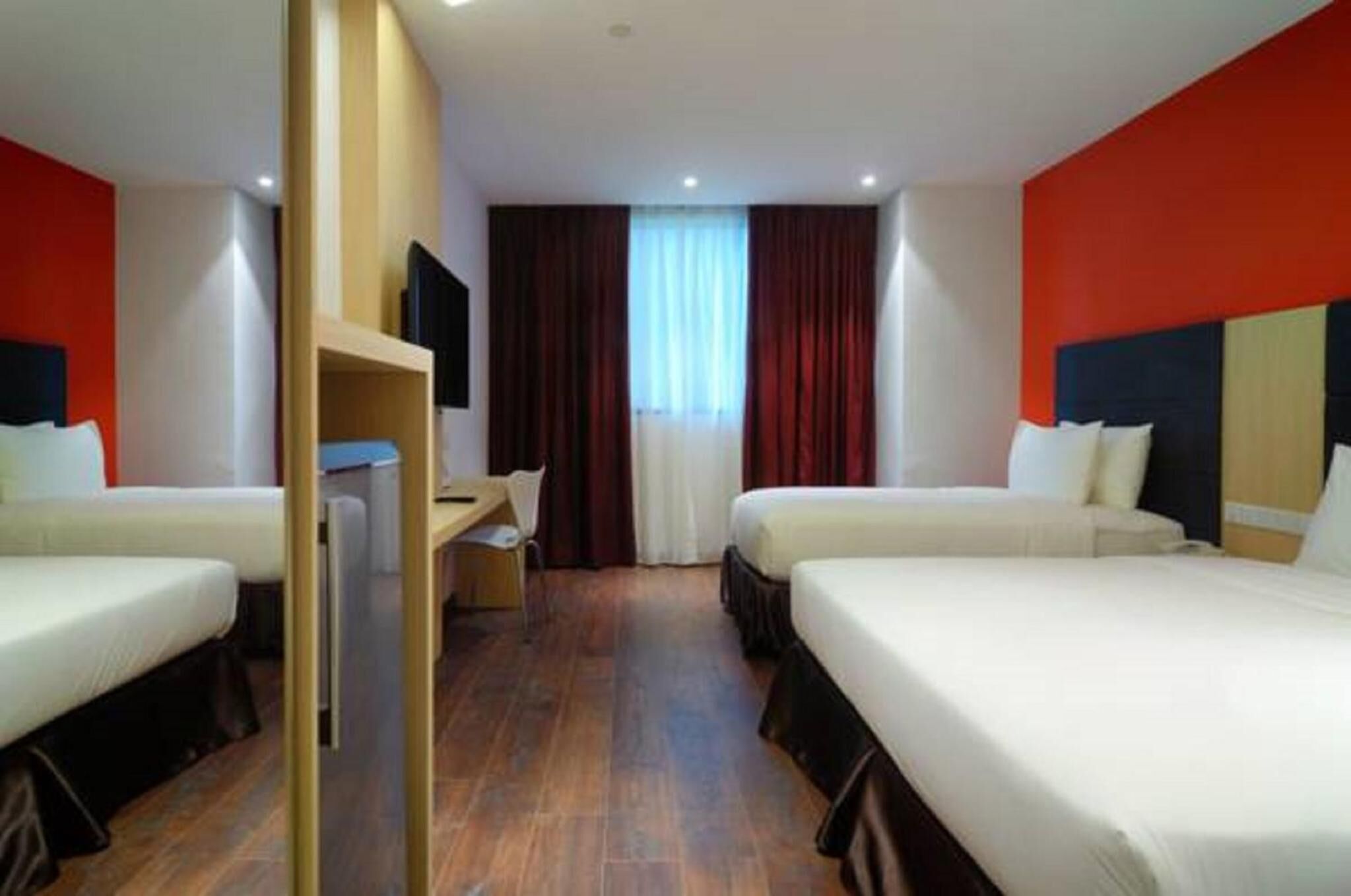 Quarto de hotel com duas camas, uma mesa e uma televisão.
