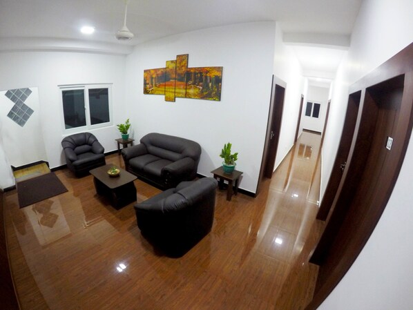 Uma sala de estar com sofá, duas poltronas, mesa de centro e um quadro na parede.