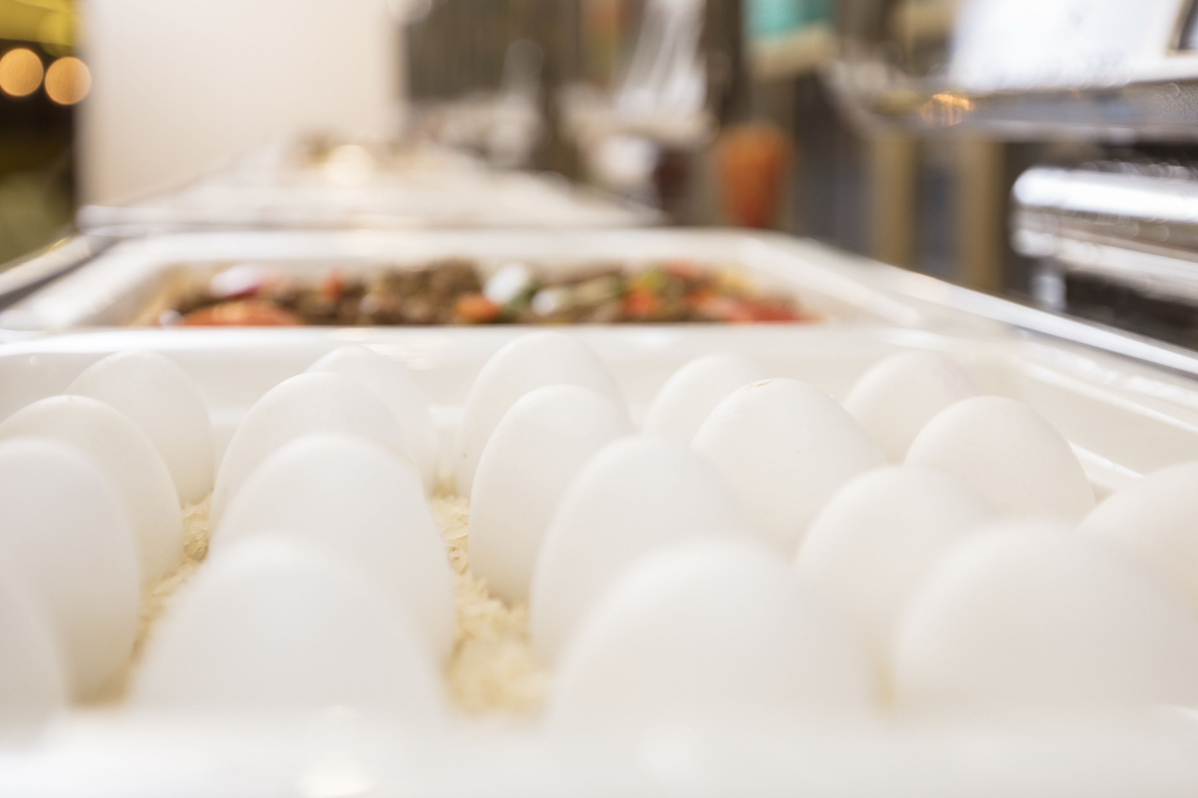 Buffet com moldes esféricos brancos repletos de comida, e um fundo desfocado com diversos pratos.