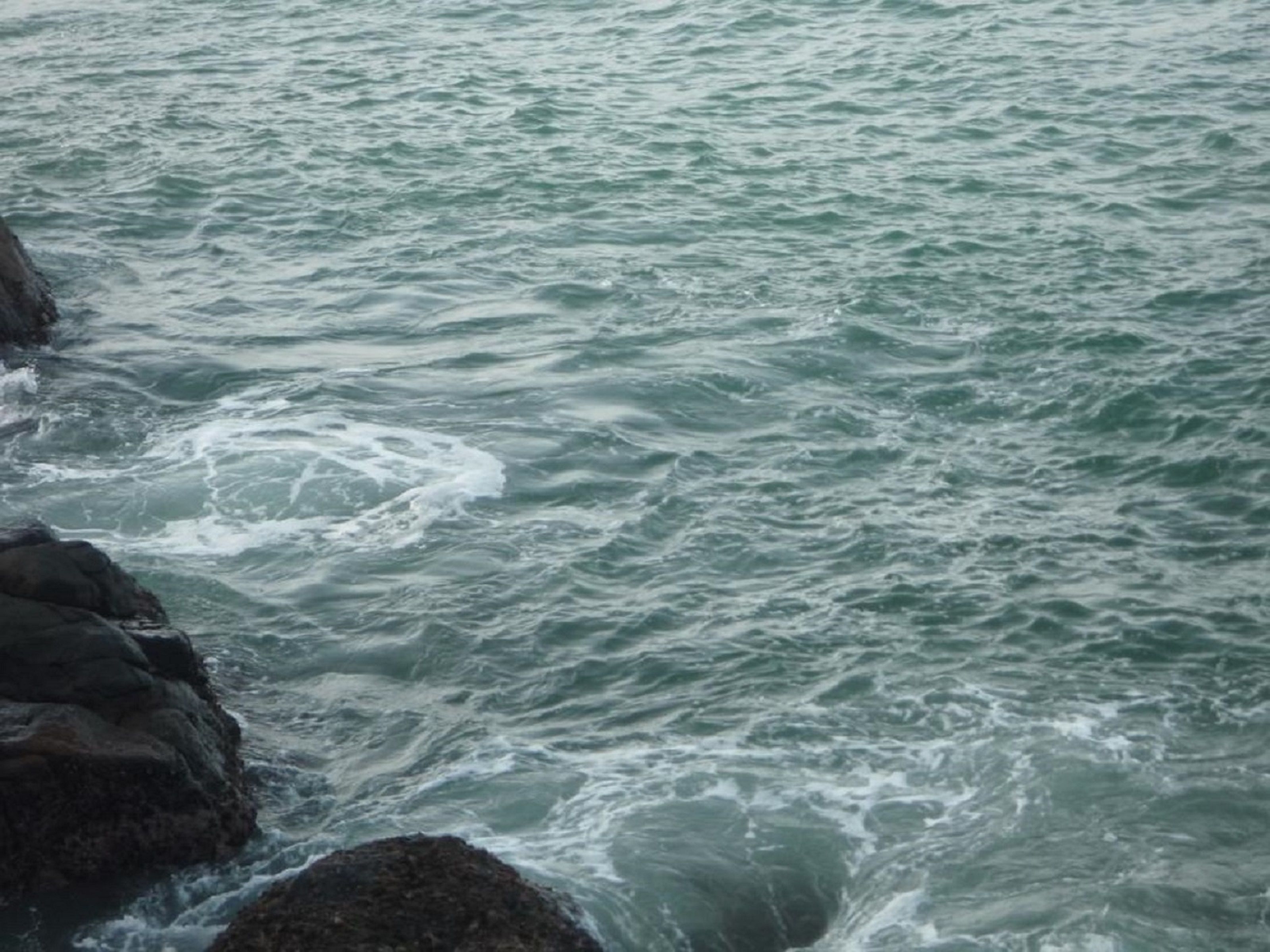 Vista de ondas do oceano quebrando contra rochas.