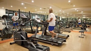 Uma academia com esteiras, espelhos e equipamentos de ginástica.