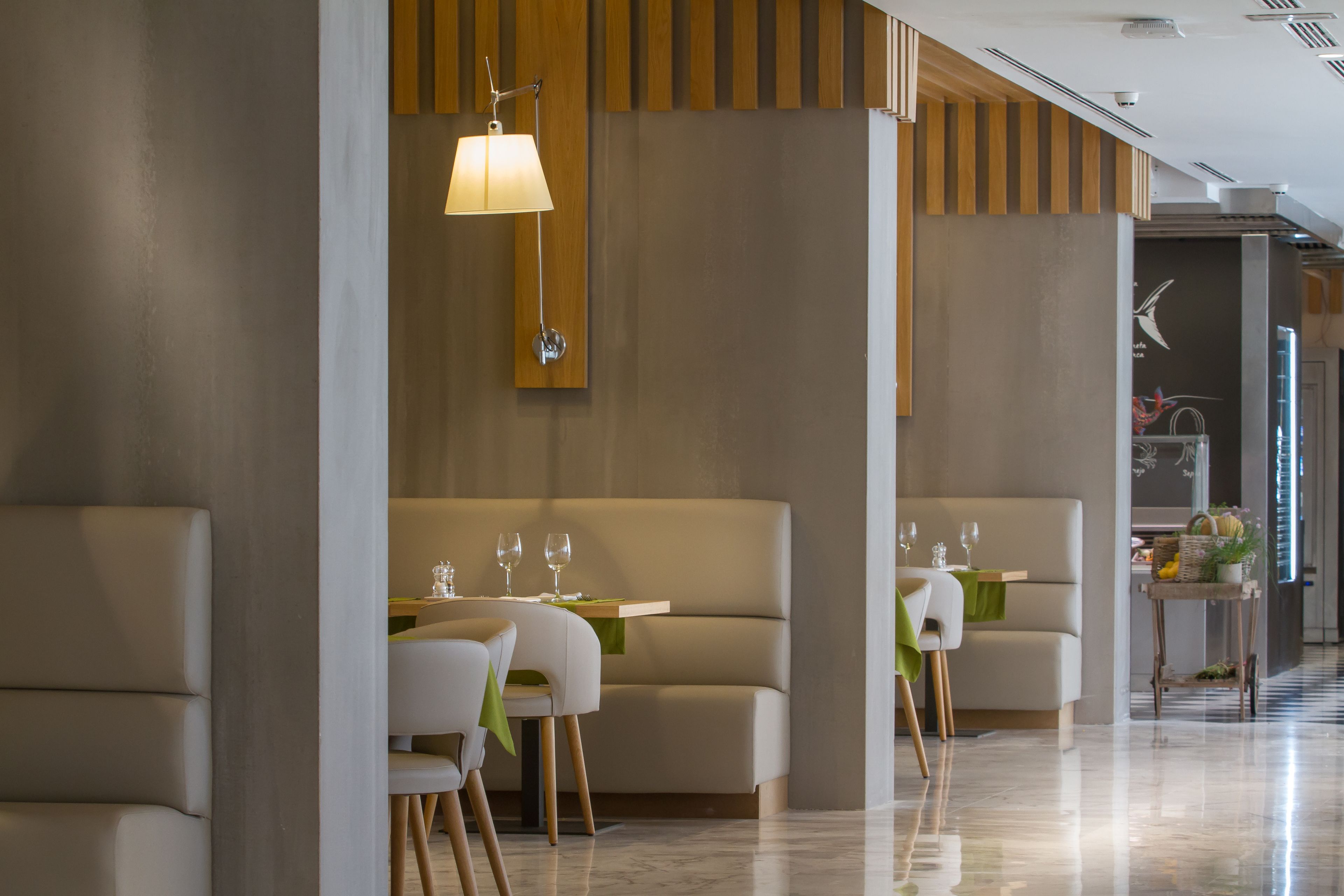 Um hall de hotel moderno com área de estar, incluindo um sofá, cadeiras, uma mesa com copos e uma luminária.
