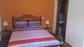 Uma cama com colcha estampada e duas luminárias laterais.
