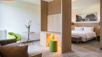 Quarto de hotel moderno com cama, uma cadeira verde, uma mesinha com uma planta e um painel de madeira.