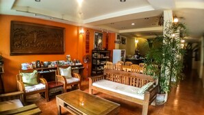 Uma sala de estar ampla com uma mesa de centro de madeira, várias cadeiras, um sofá e uma estante de livros.