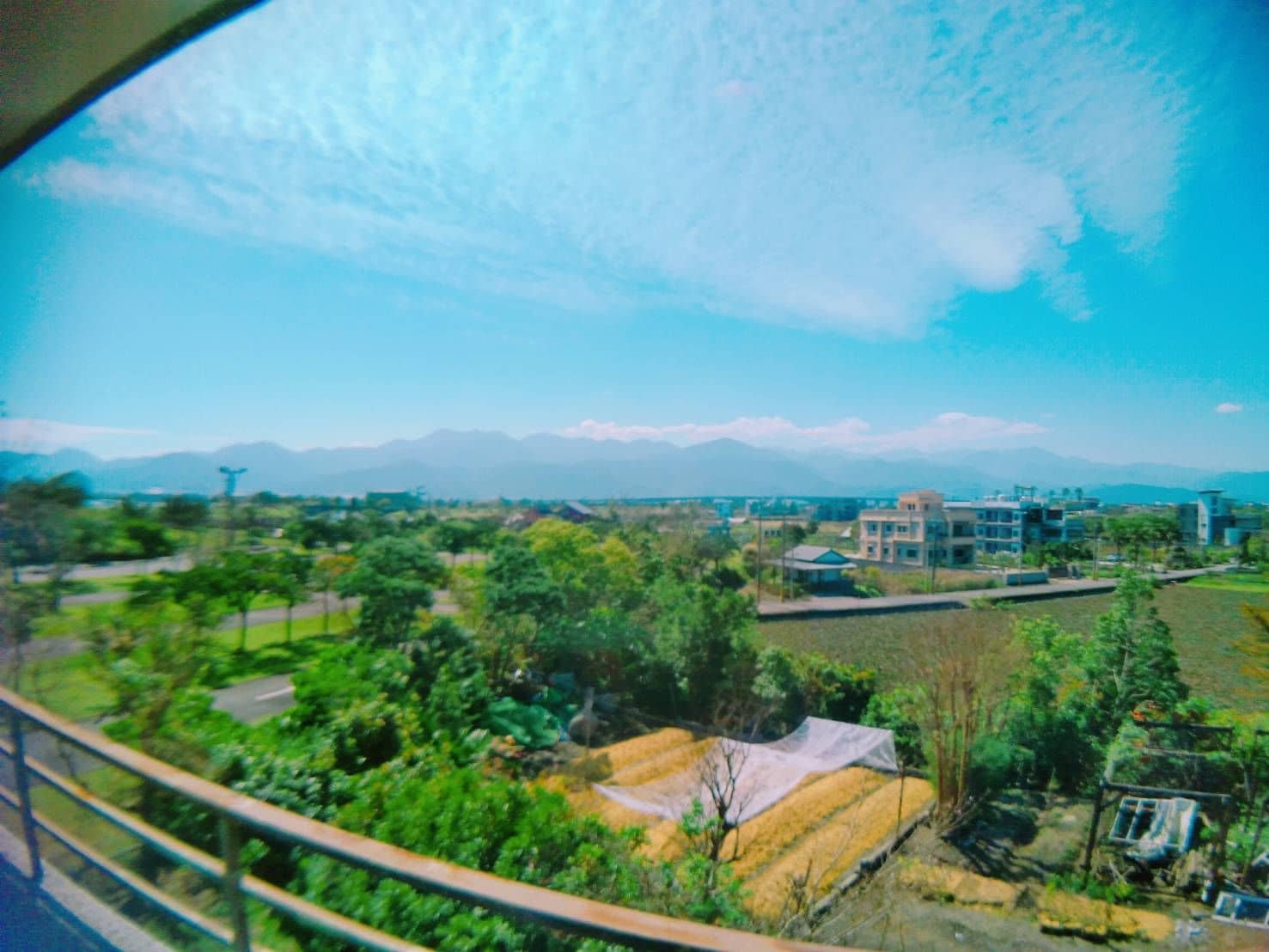 Vista panorâmica de uma área residencial com casas, vegetação e montanhas ao longe.