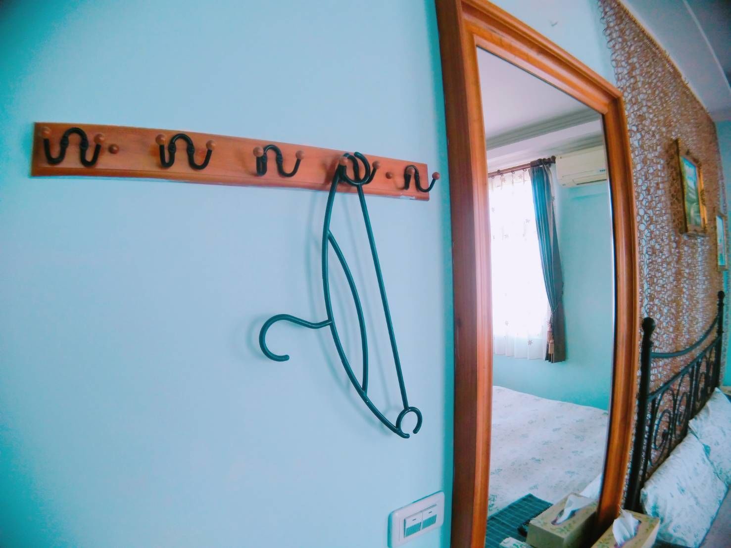 Quarto com um porta-roupas de madeira, um espelho e uma cama com colchão branco e roupa de cama florida.