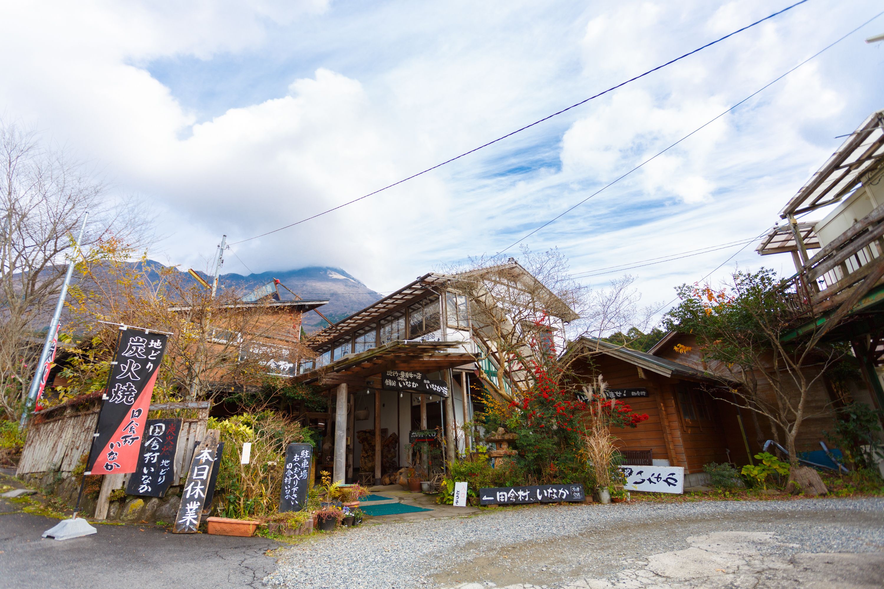 Um edifício japonês tradicional com fachada de madeira, entrada coberta e placas em japonês.