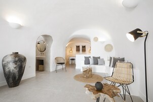 Uma sala de estar moderna com um vaso grande, uma mesa de centro de madeira e um sofá com almofadas.