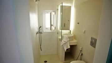 Casa de banho pequena e compacta, com chuveiro, sanita e lavatório.