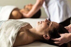 Uma pessoa deitada na cama recebendo uma massagem.