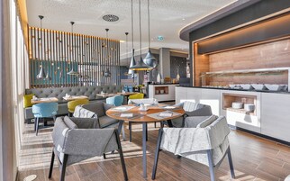 Interior moderno de restaurante com área de bar, arranjos de assentos e balcão de buffet.