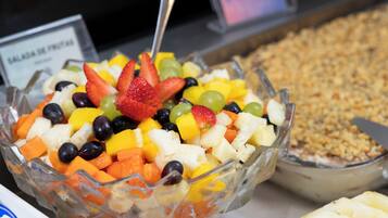 Uma tigela de salada de frutas com diversas frutas e uma colher.