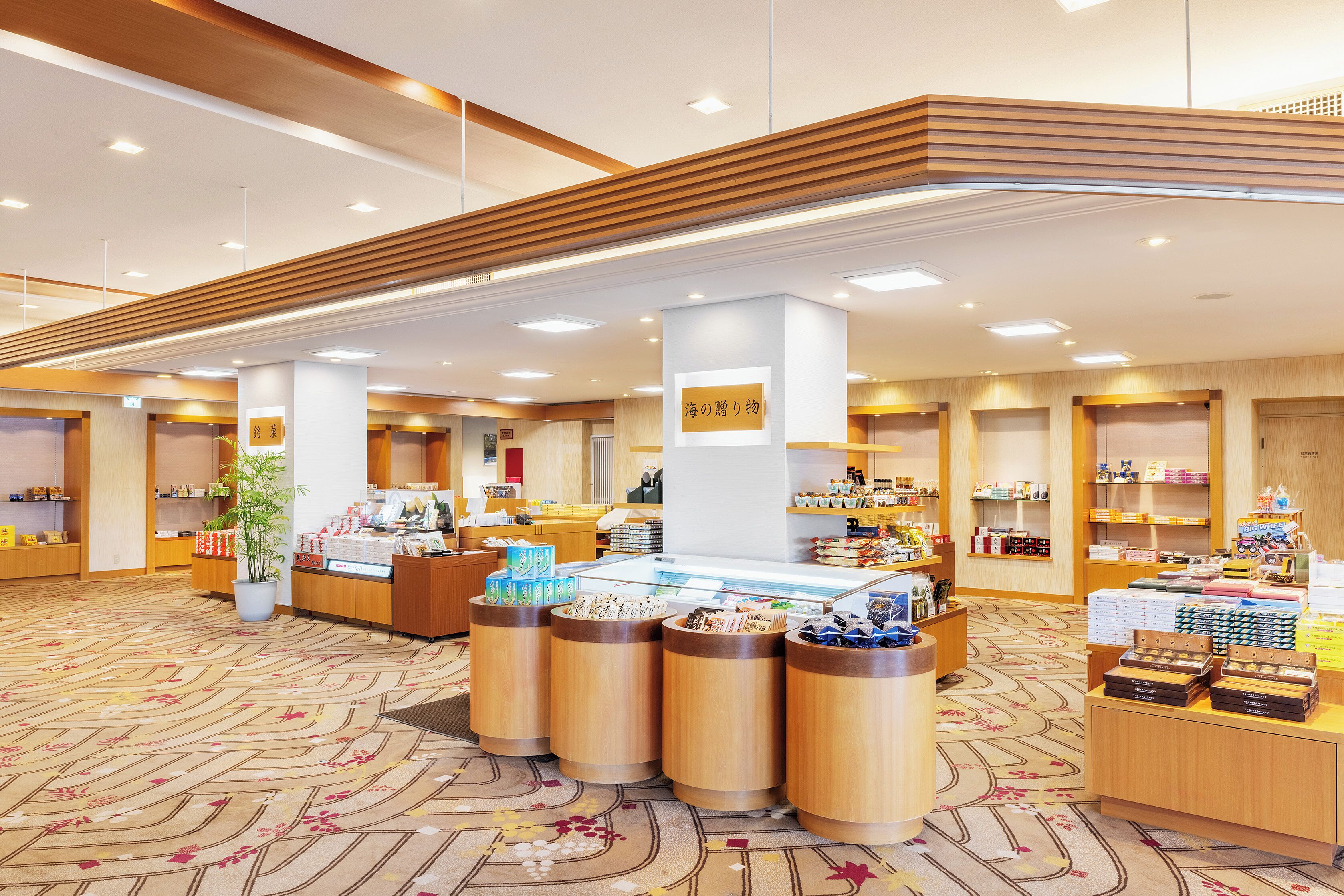 Um lobby de hotel com uma recepção central, vários balcões e um tapete estampado.