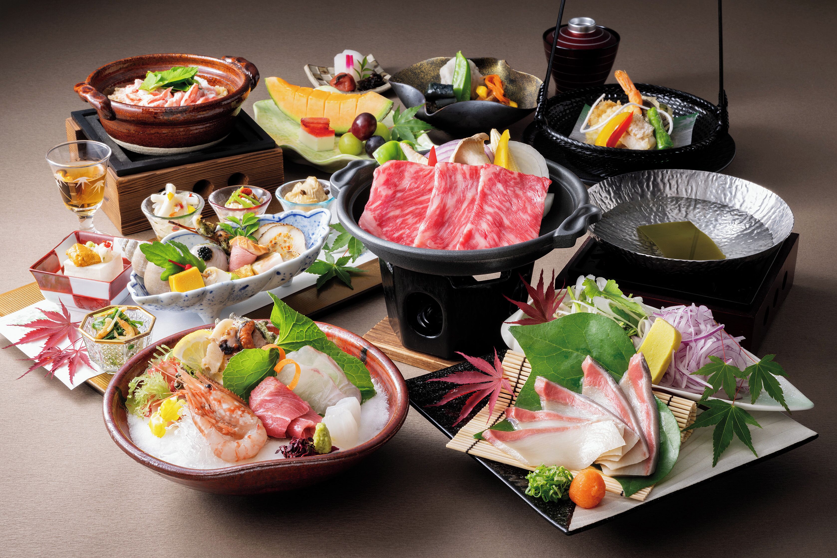 Diversos pratos japoneses, incluindo sashimi, legumes e um pote quente, dispostos sobre uma mesa.