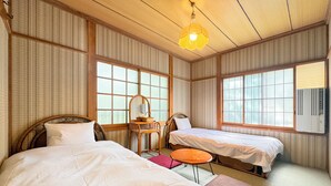 Quarto com duas camas, teto de madeira e grandes janelas.