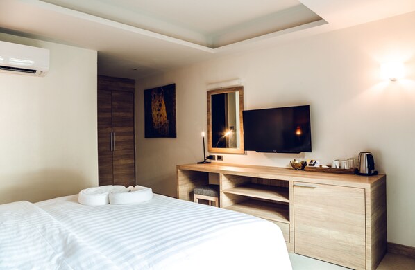 Quarto de hotel moderno com uma cama, uma escrivaninha de madeira, uma televisão e um ar condicionado fixado na parede.