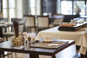 Uma mesa de jantar com uma chávena, saleiro e pimenteiro, e um recipiente de vidro com frutos secos.