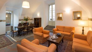 Uma sala de estar ampla com sofás laranja, uma mesa de centro e uma área de jantar com uma mesa e cadeiras de madeira.